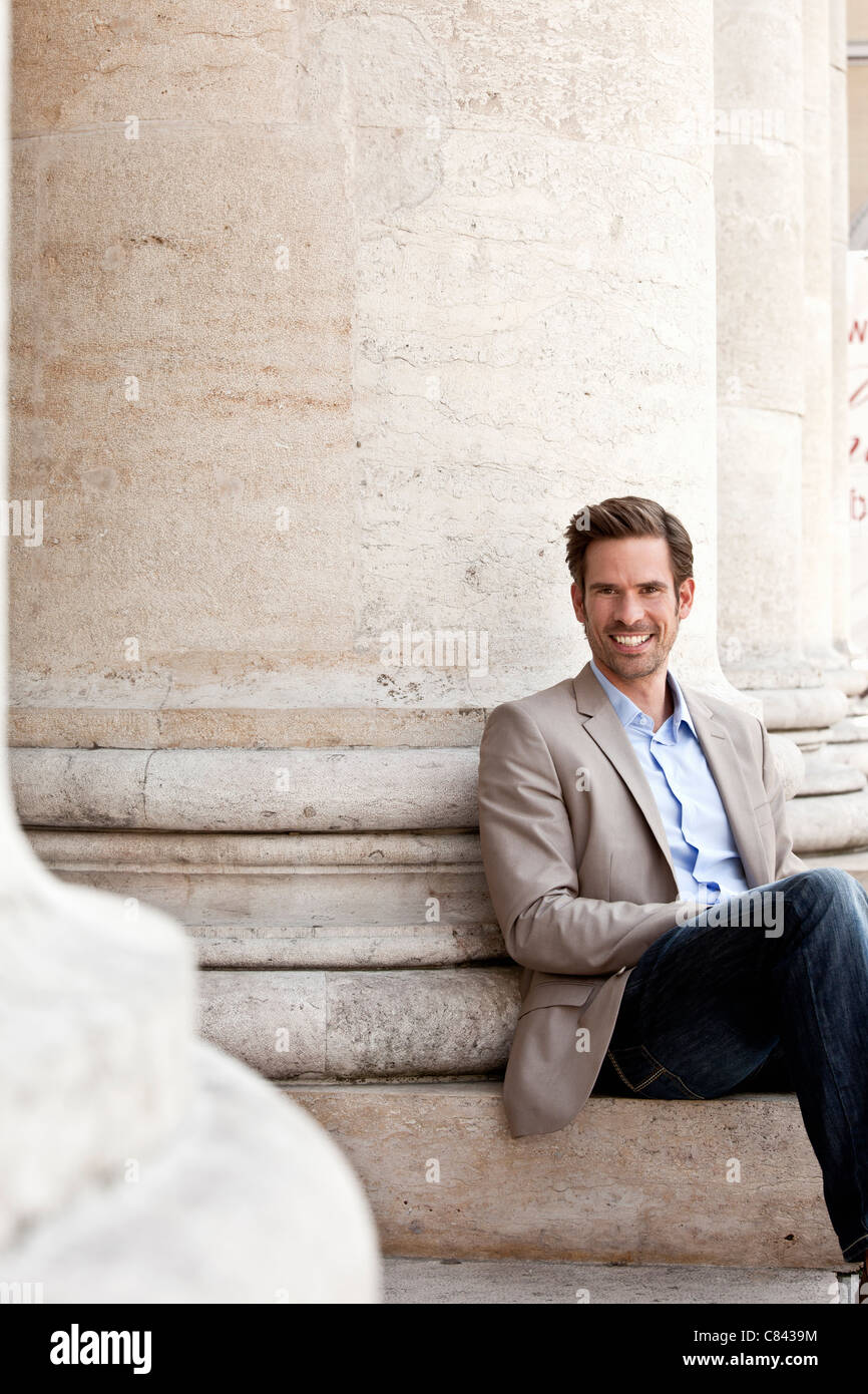 Man sitting on columned building Stock Photo - Alamy