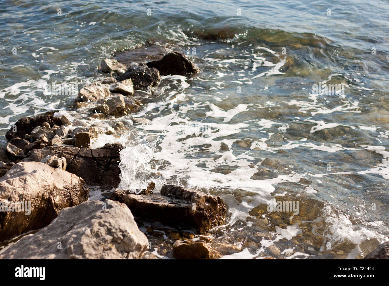 Small wave crashing on rocks Stock Photo - Alamy