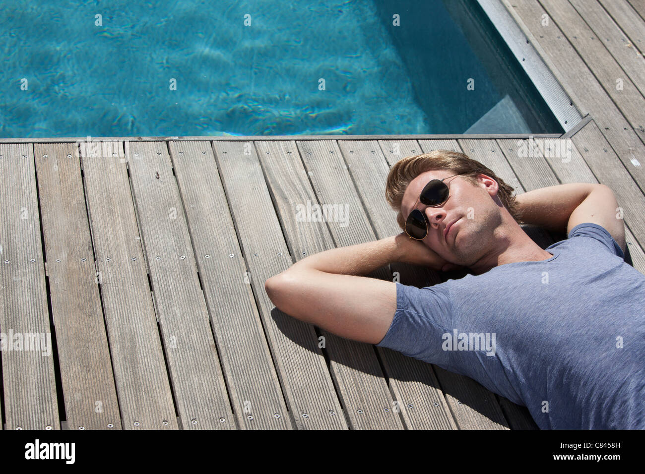 Man relaxing by swimming pool Stock Photo - Alamy