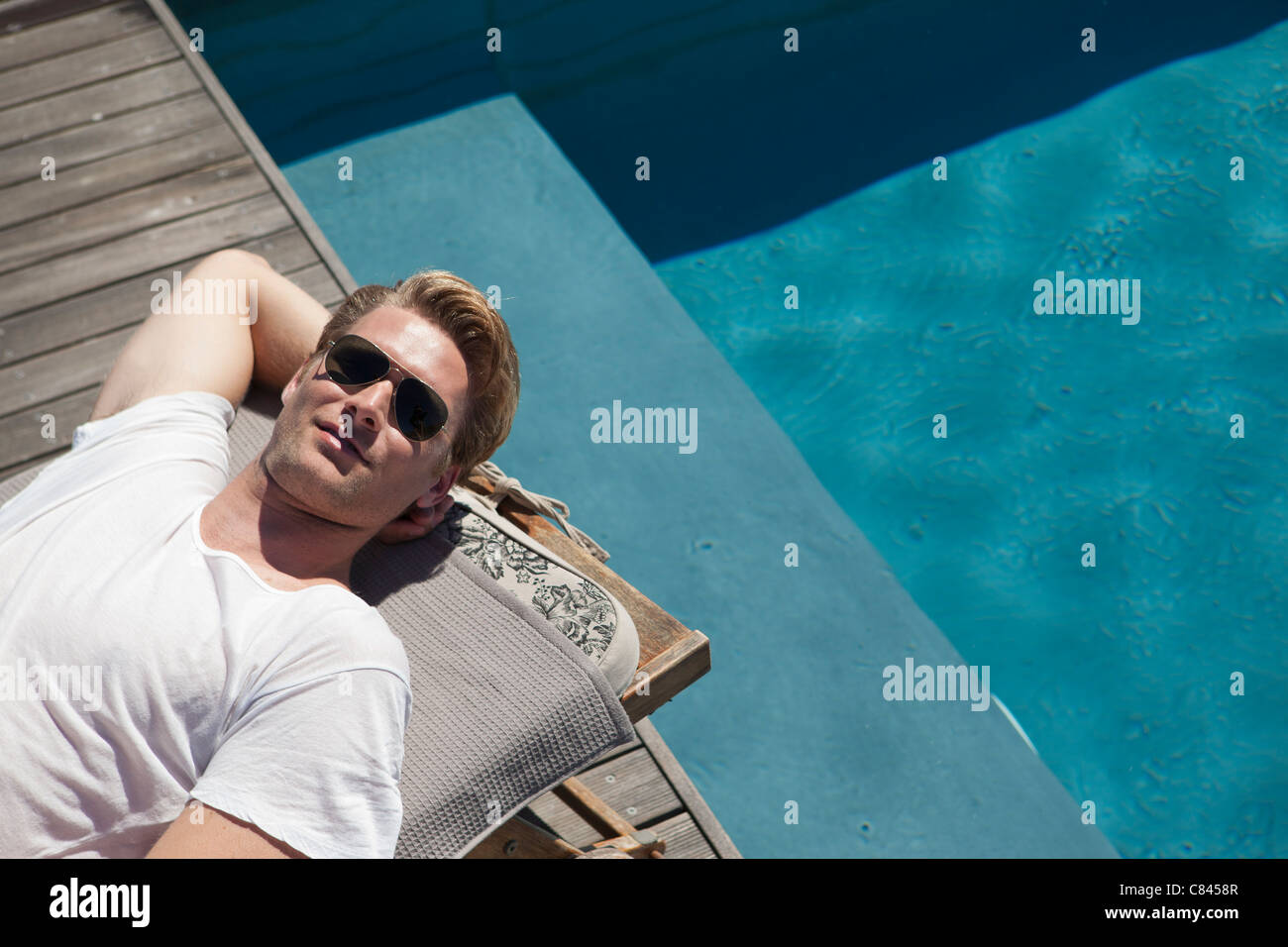 Man relaxing by swimming pool Stock Photo - Alamy
