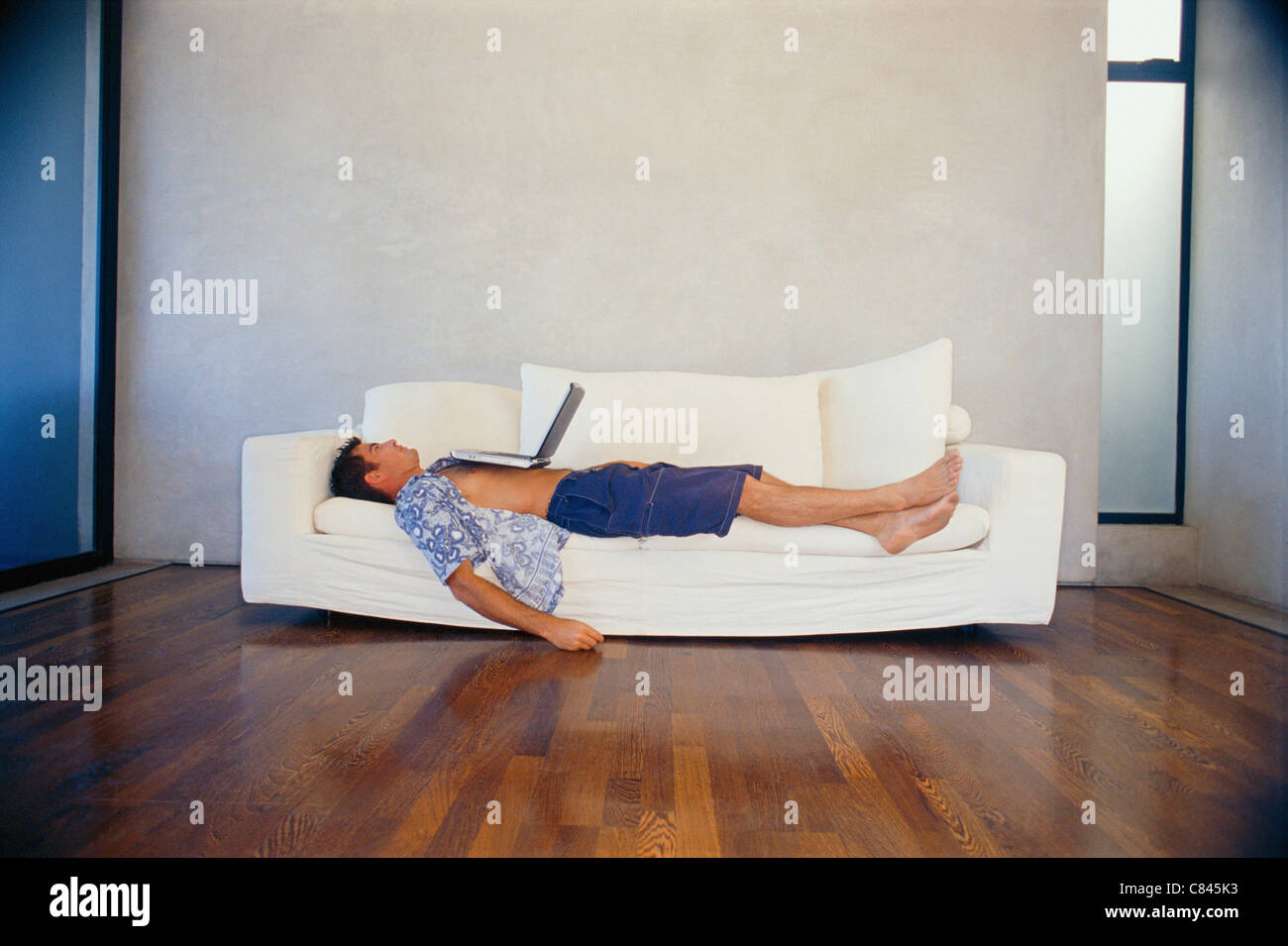 Man sleeping with laptop on couch Stock Photo - Alamy