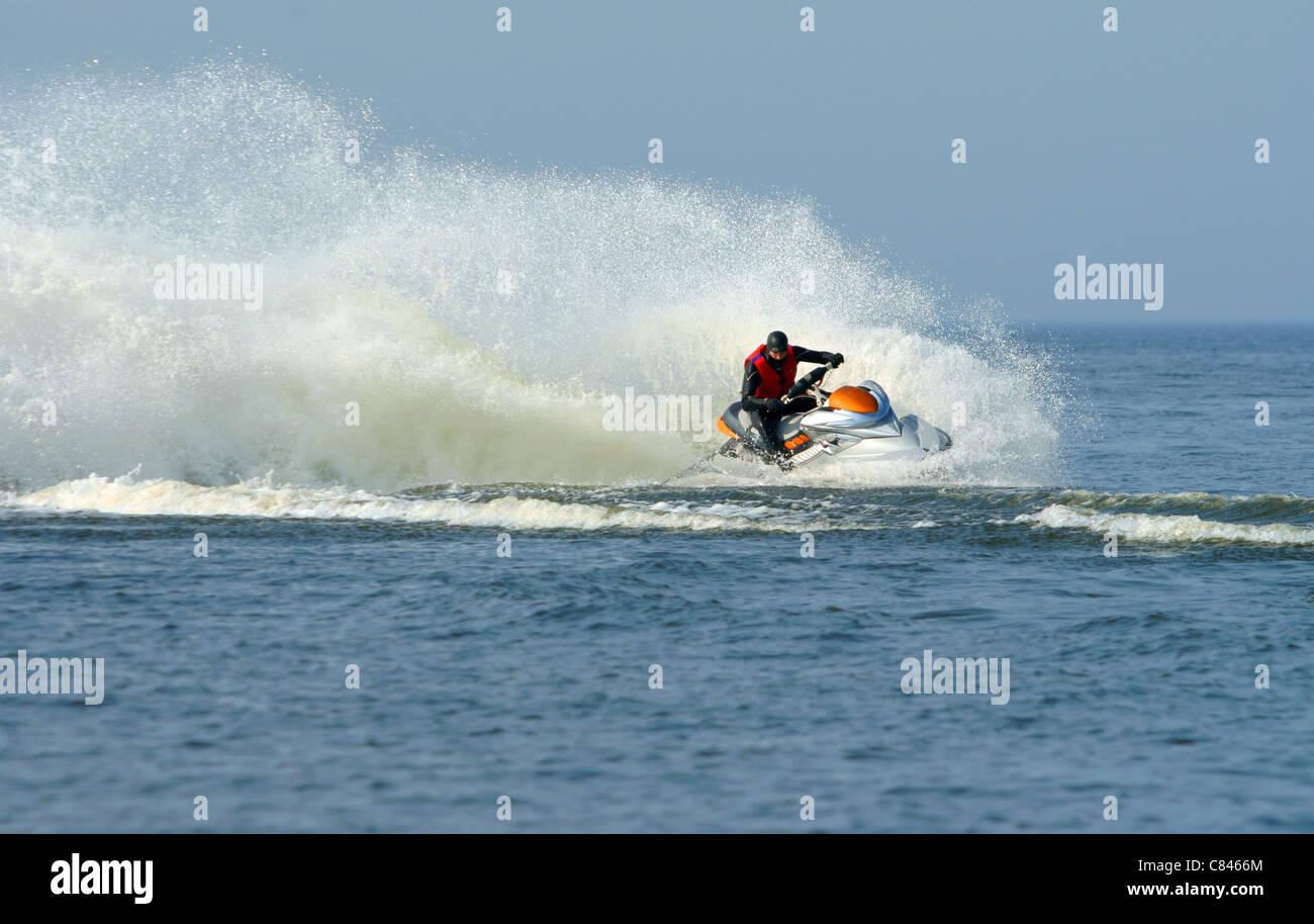 Backlit jet ski with water spray on the blue sea. Jetski in action, man ...