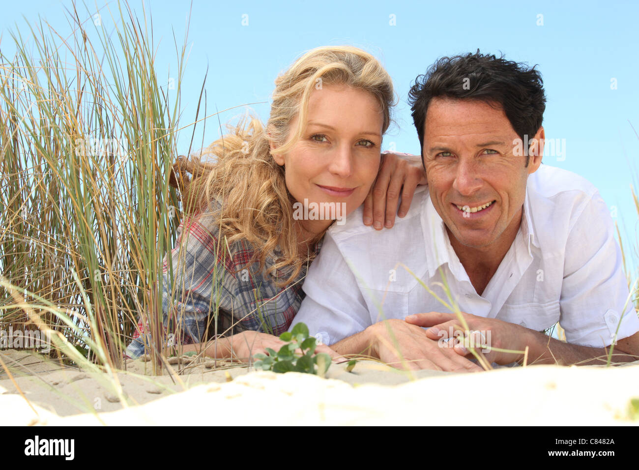 Couple lying on the sand Stock Photo - Alamy