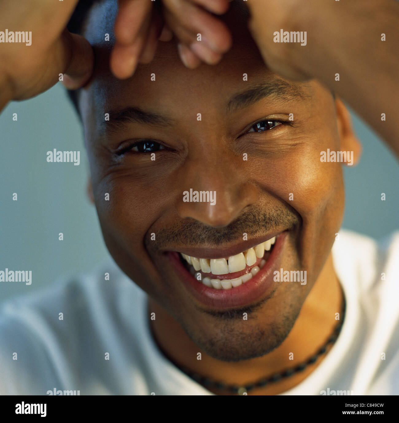 Grinning man with head in hands Stock Photo - Alamy