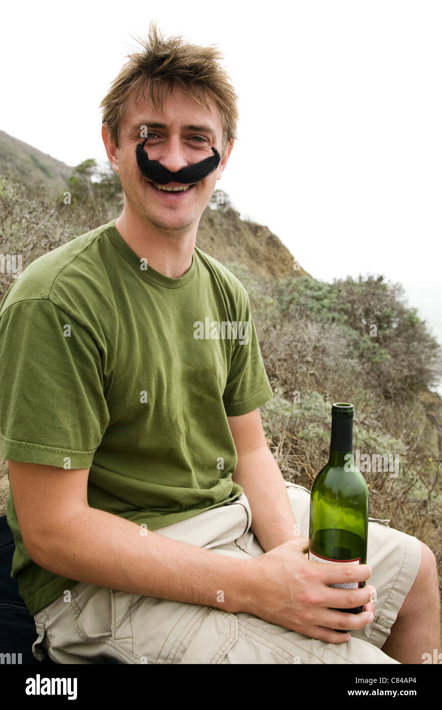 Caucasian man in costume mustache holding wine bottle Stock Photo - Alamy