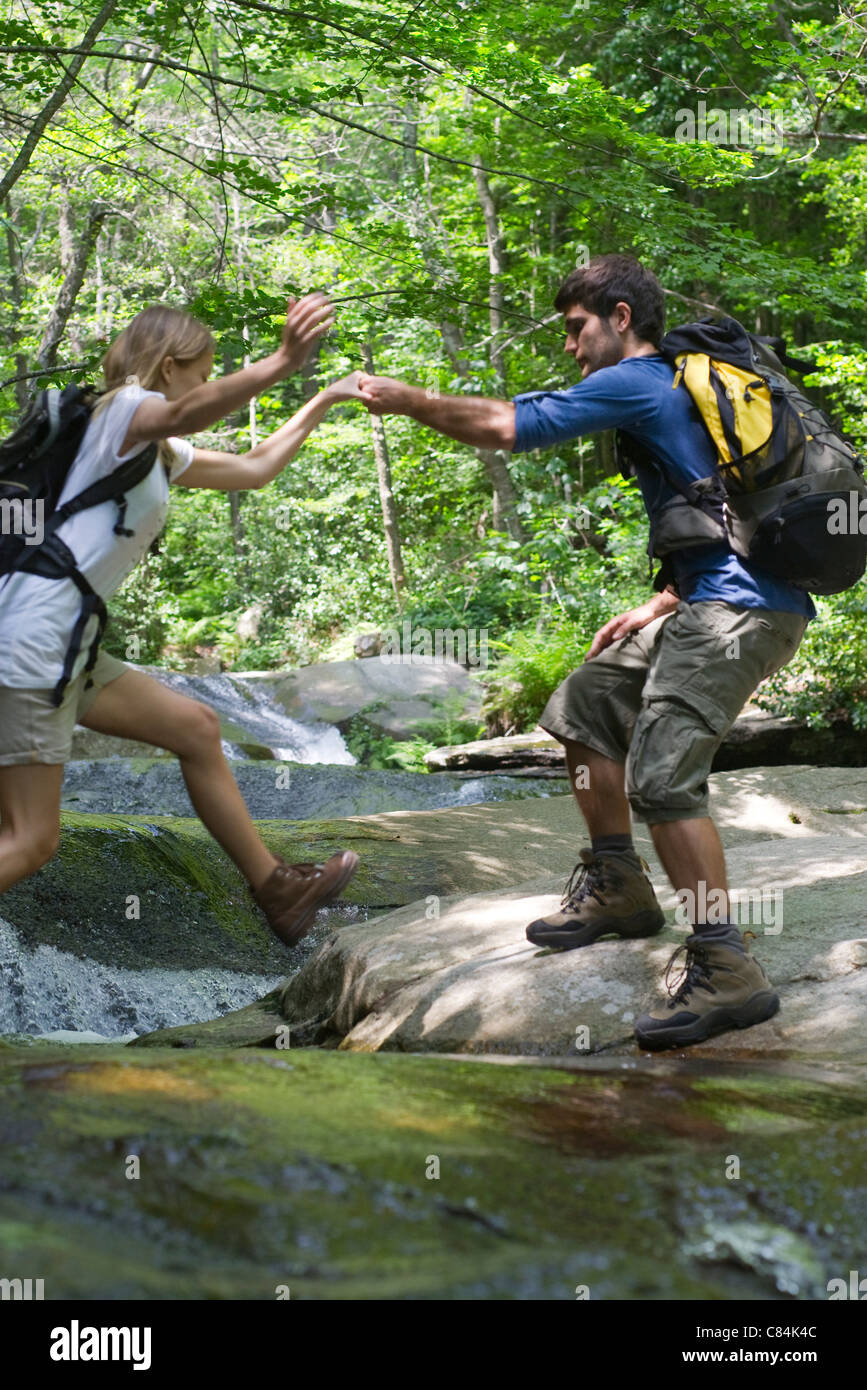 Man helping woman crossing stream Stock Photo - Alamy