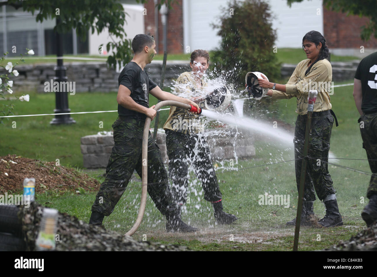 Military man spraying a fire hose, girl stopping the spray with a ...