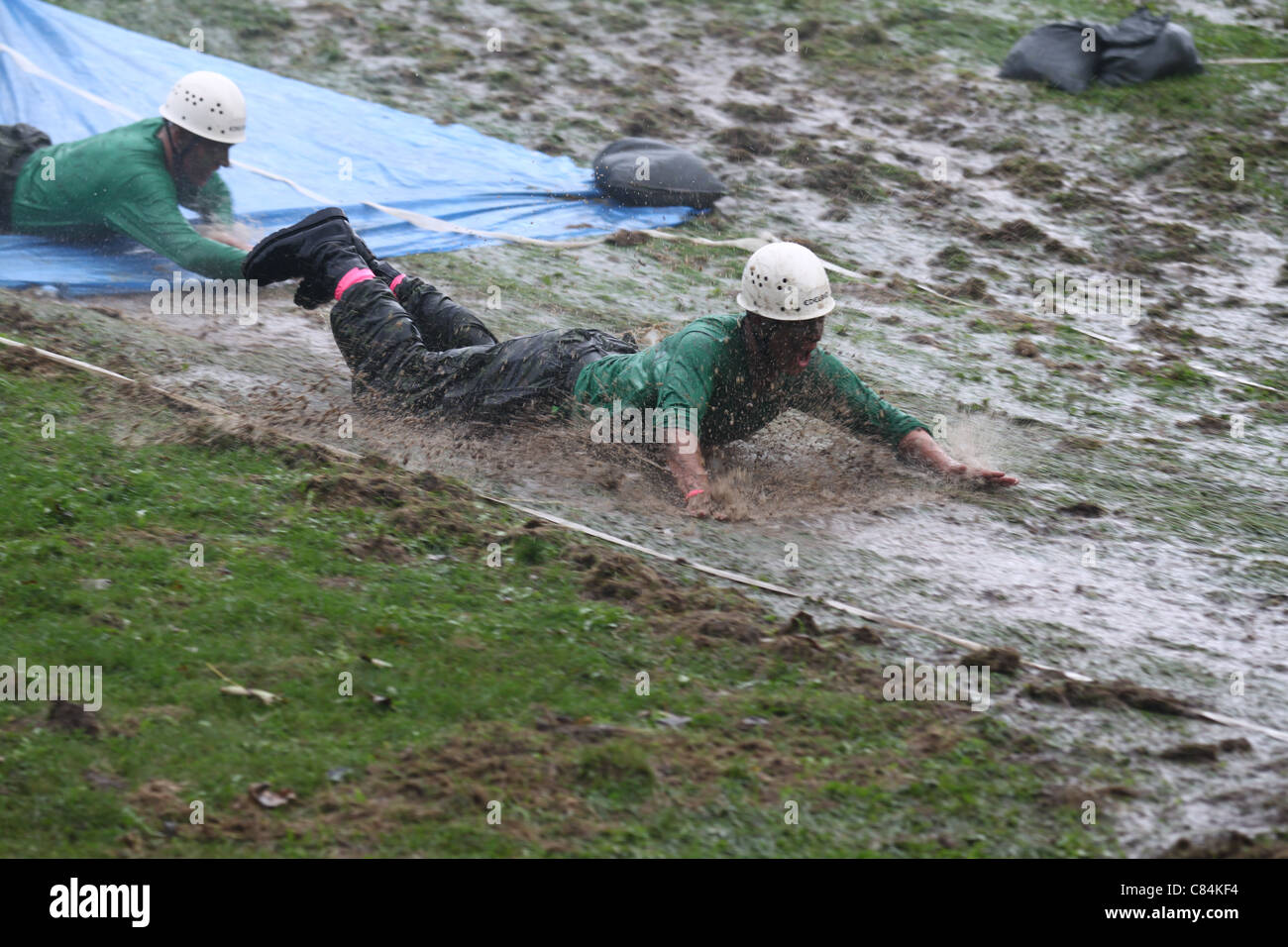 Two males sliding down a muddy slope Stock Photo - Alamy