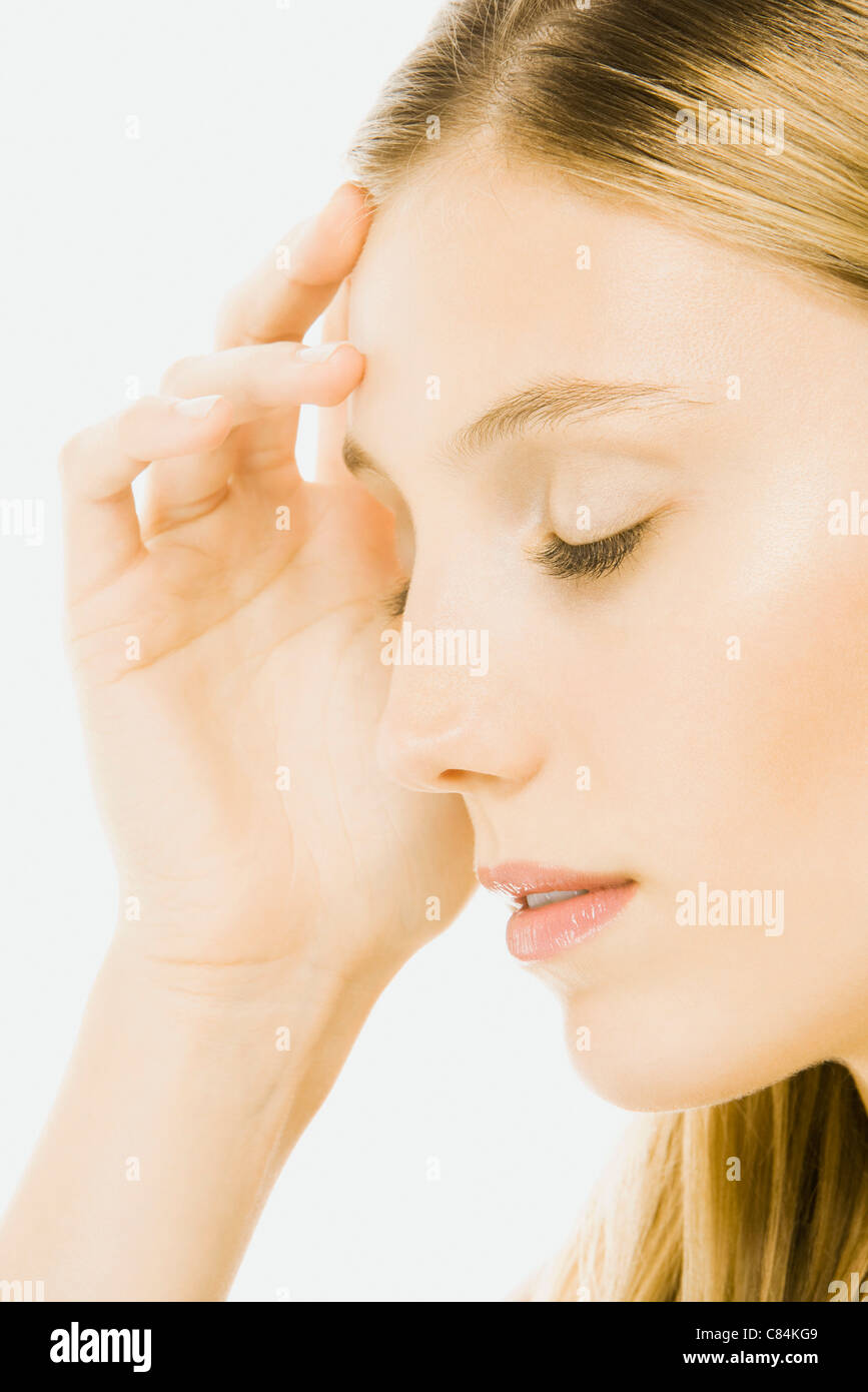 Woman with eyes closed, touching forehead, side view Stock Photo - Alamy