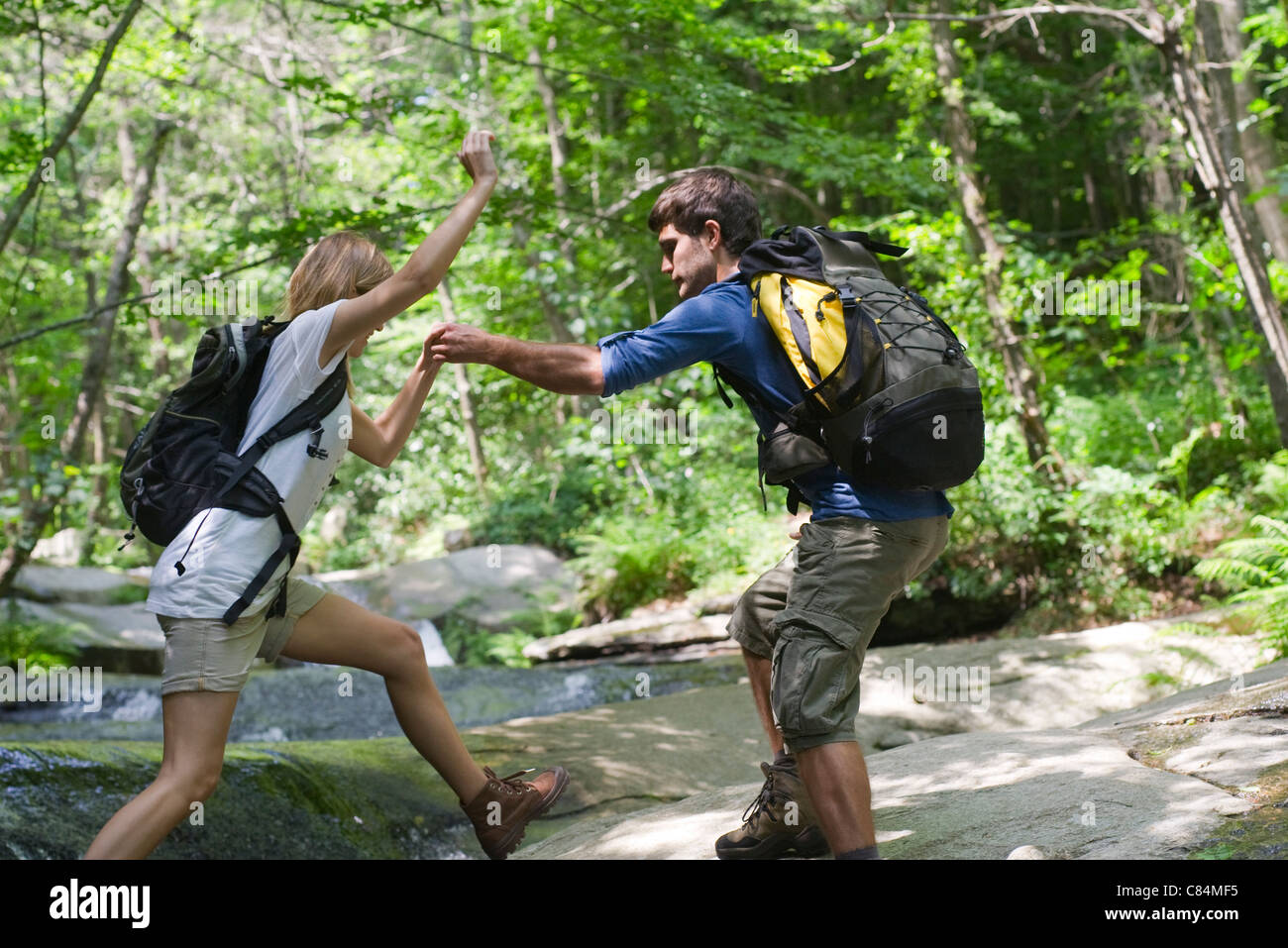 Man helping woman crossing stream Stock Photo - Alamy