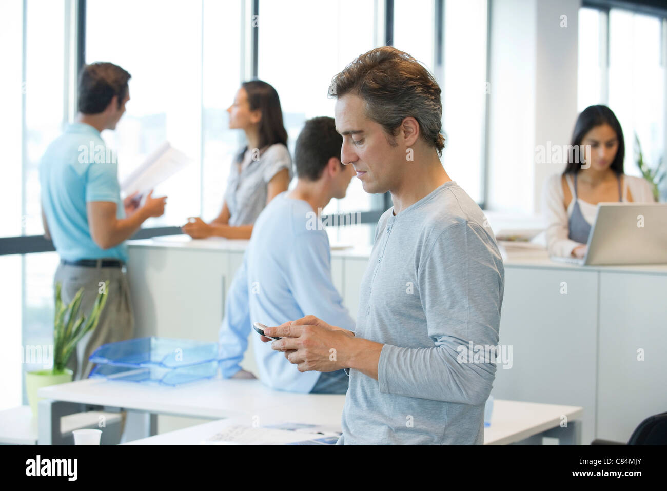 Man text messaging with cell phone in office Stock Photo - Alamy