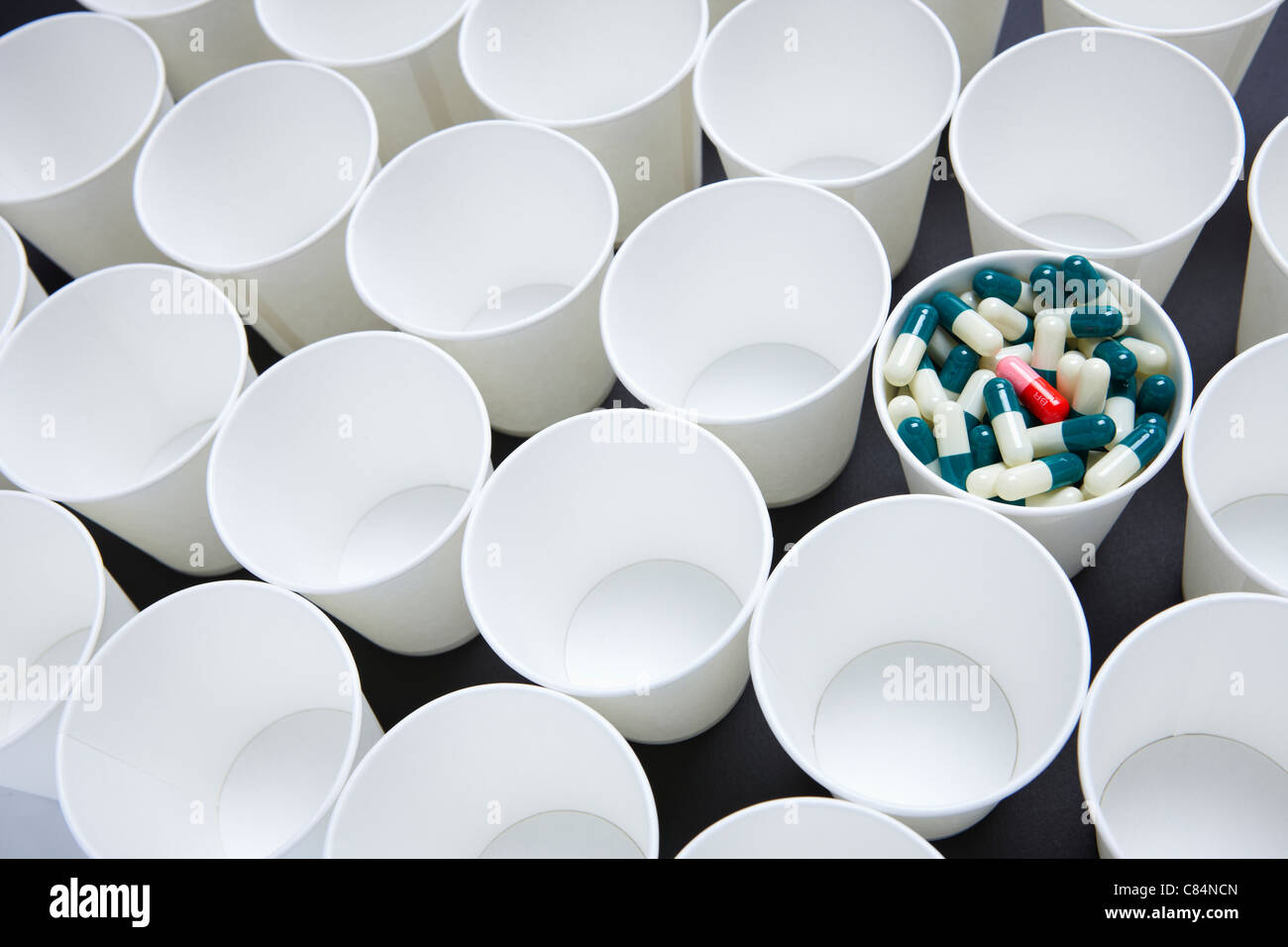 A cup full of tablets with other paper cups empty Stock Photo - Alamy
