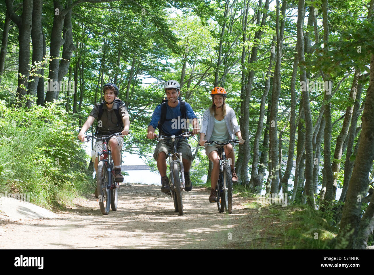 Friends riding bicycles side by side through woods Stock Photo - Alamy