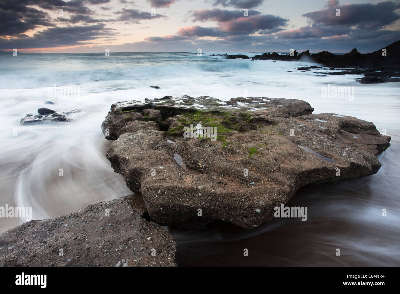 Waves washing over rocks on beach Stock Photo - Alamy