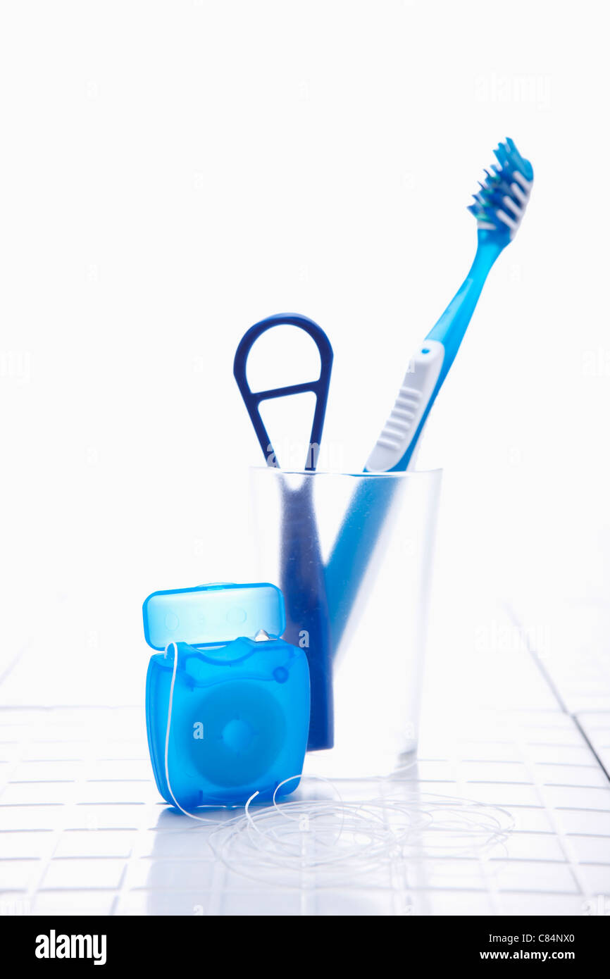 Blue tooth brush, tongue cleaner in cup and floss Stock Photo - Alamy