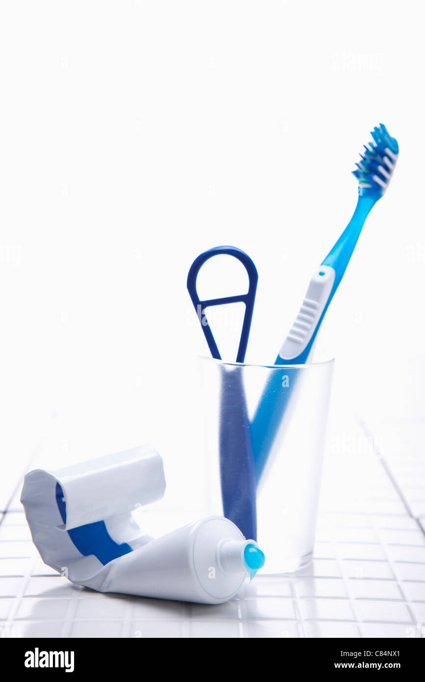 Blue tooth brush, tongue cleaner in cup and tooth paste Stock Photo - Alamy