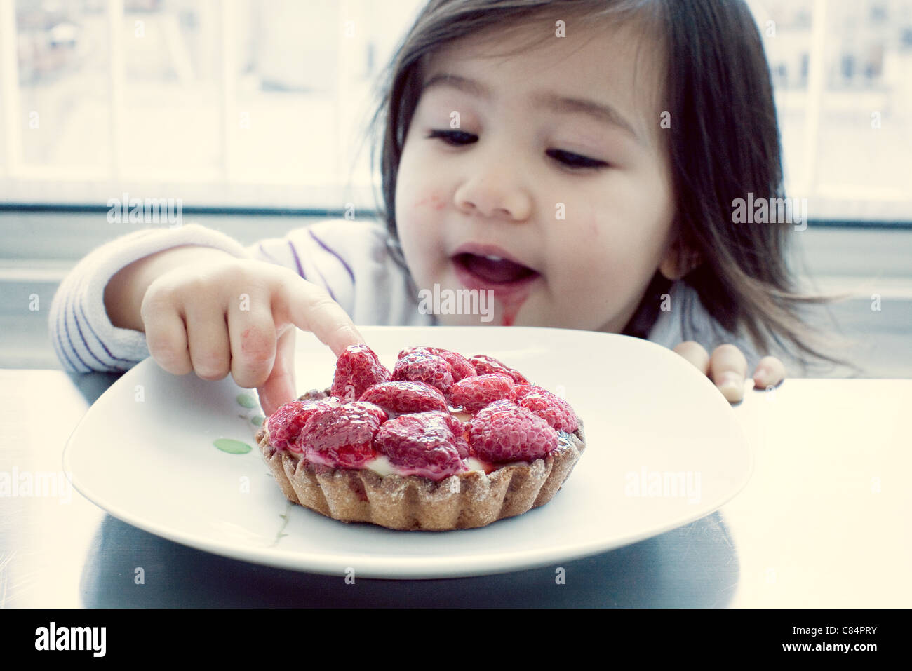 Little girl getting taste of raspberry tart Stock Photo - Alamy