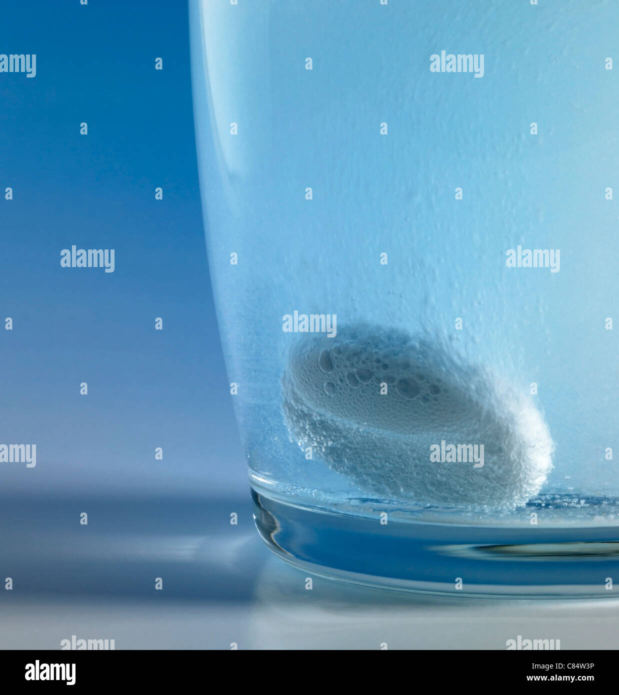 closeup studio shot of a dissolving fizzy tablet in a glass of water ...