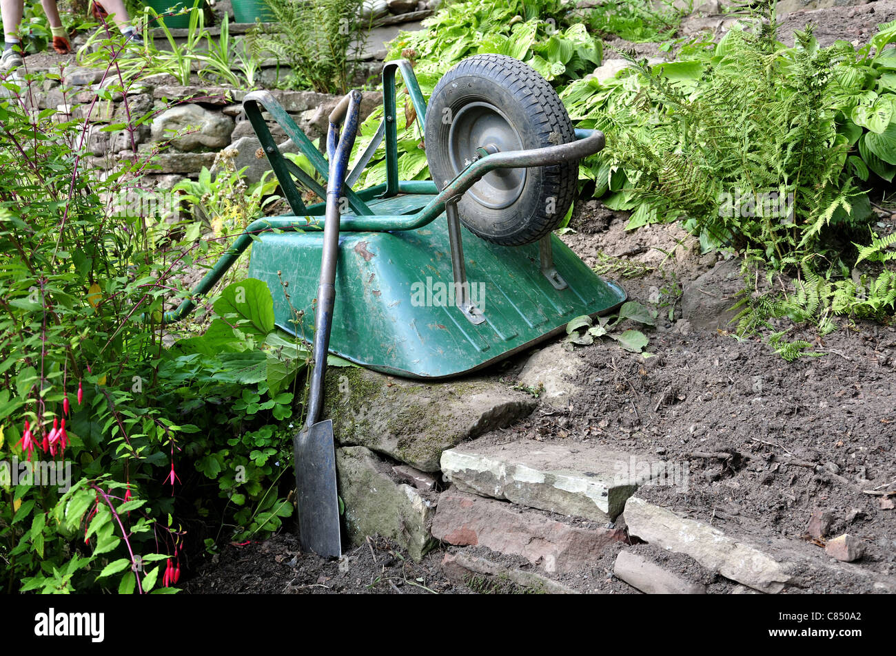 Upside down wheelbarrow with spade leaning on it Stock Photo - Alamy
