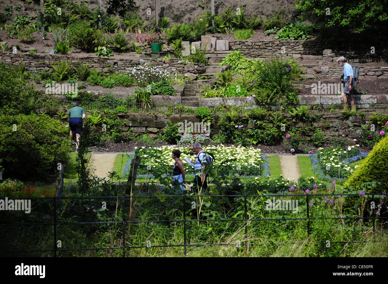 Volunteers working in Quarry Bank Mill gardens and visitors on path ...