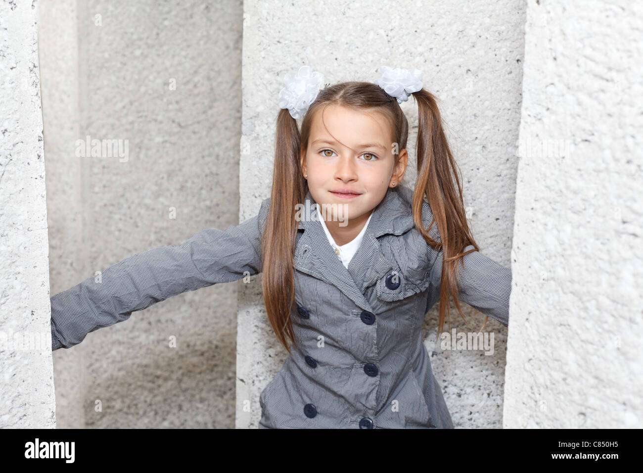 Portrait of a young girl with long tails in a gray coat. Russian child ...