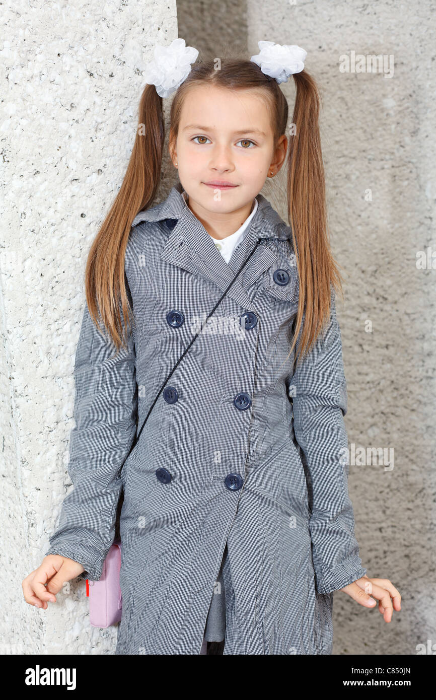 Portrait of a young girl with long tails in a gray coat. Russian child ...