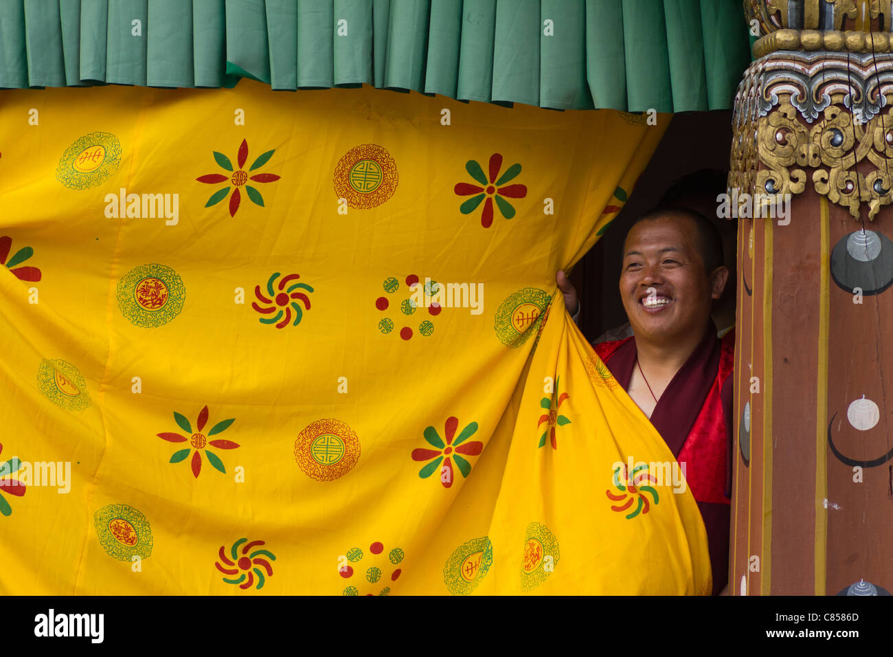 Monk smiling behind curtain during Thimphu festival Stock Photo - Alamy