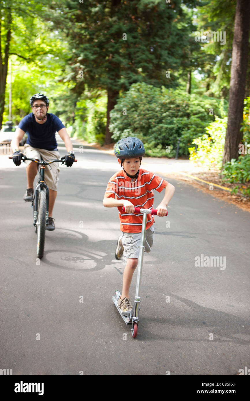 Boy Riding Scooter with Father following on Bicycle, Washington Park ...