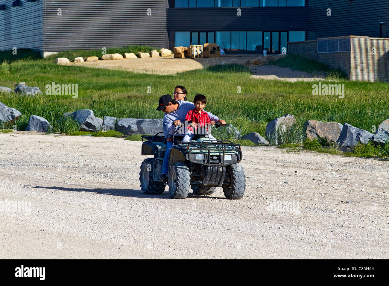 Native family (mother, father and young boy) rides a four wheel ATV ...