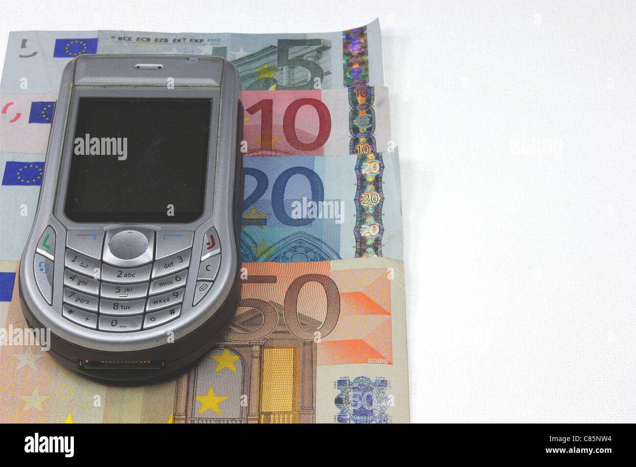 Old and used cell phones next to different euro notes to represent the ...