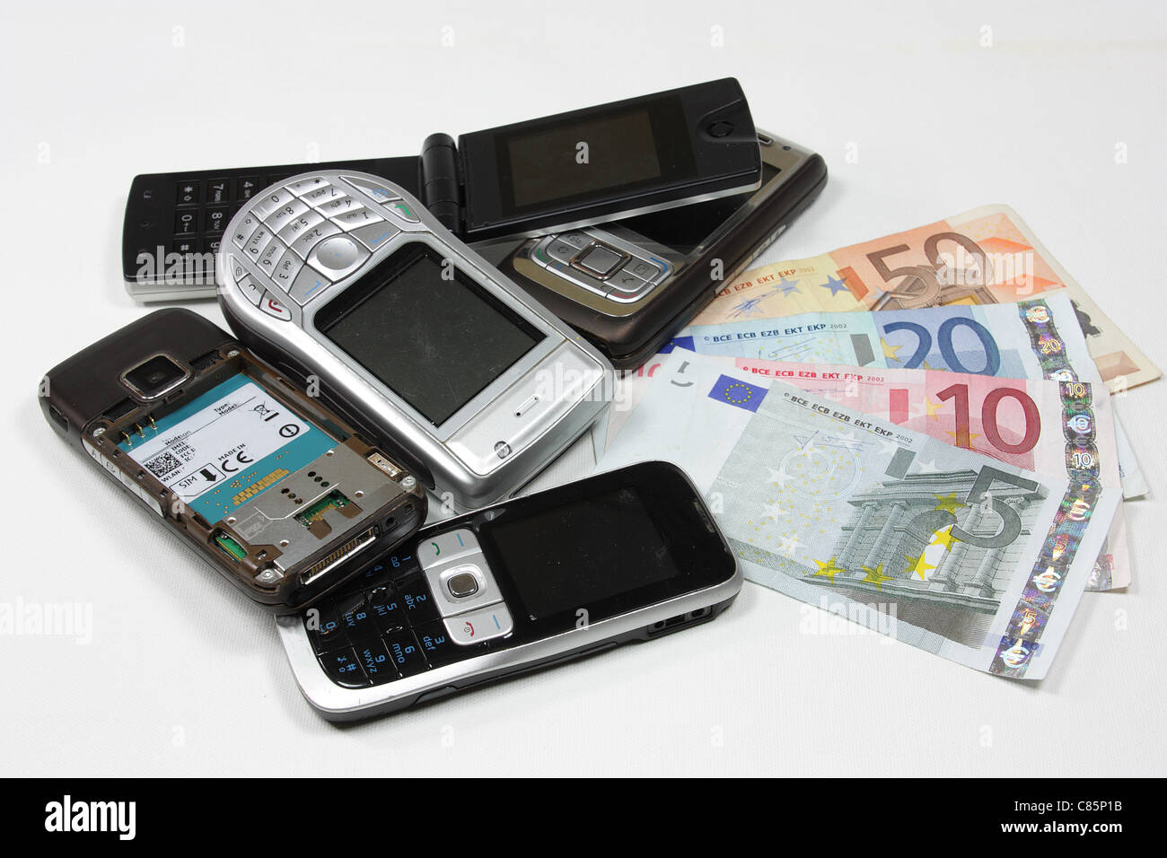Old and used cell phones next to different euro notes to represent the ...