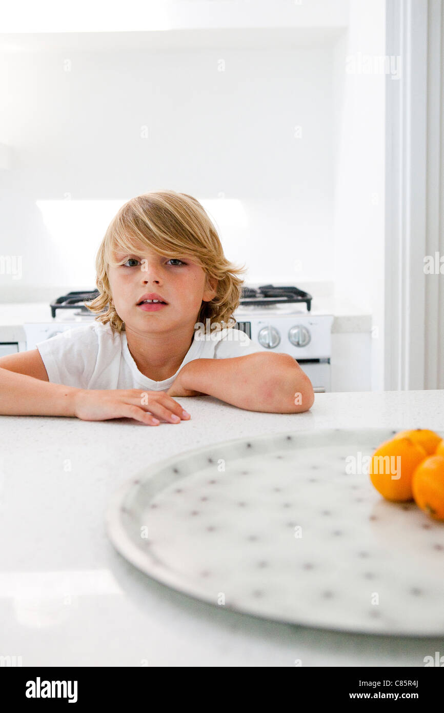 Young boy sitting at kitchen counter Stock Photo - Alamy