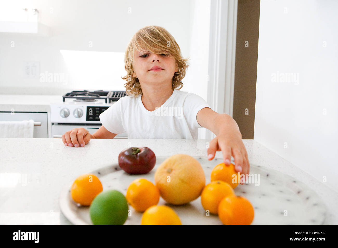 Young boy selecting fruit off tray Stock Photo - Alamy