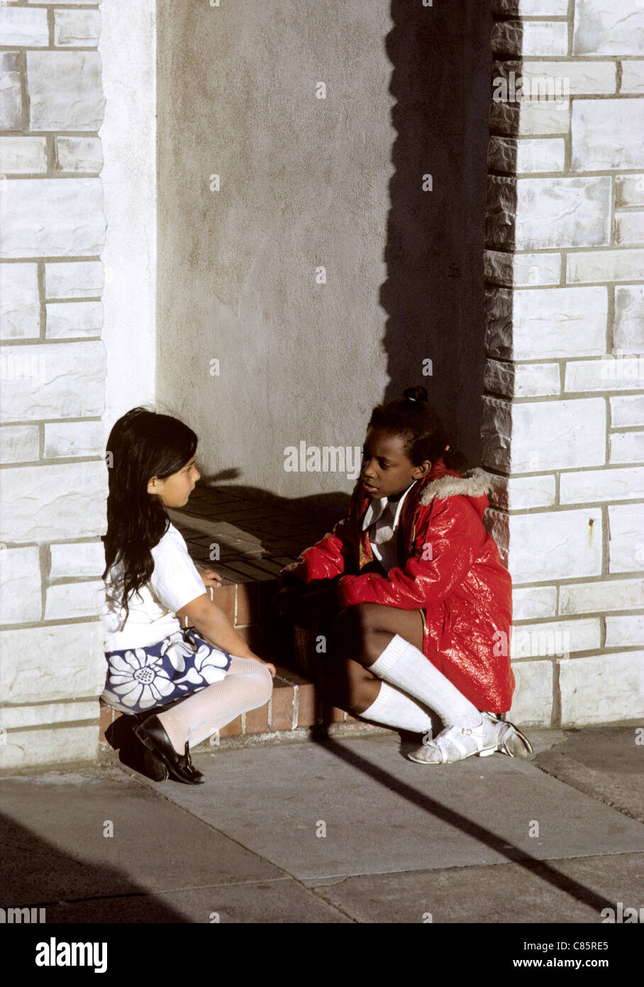 two inner city kids, one black, one hispanic, talk while sitting in a ...