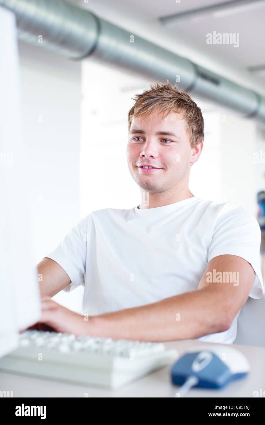 handsome college student using a computer in a college/university ...