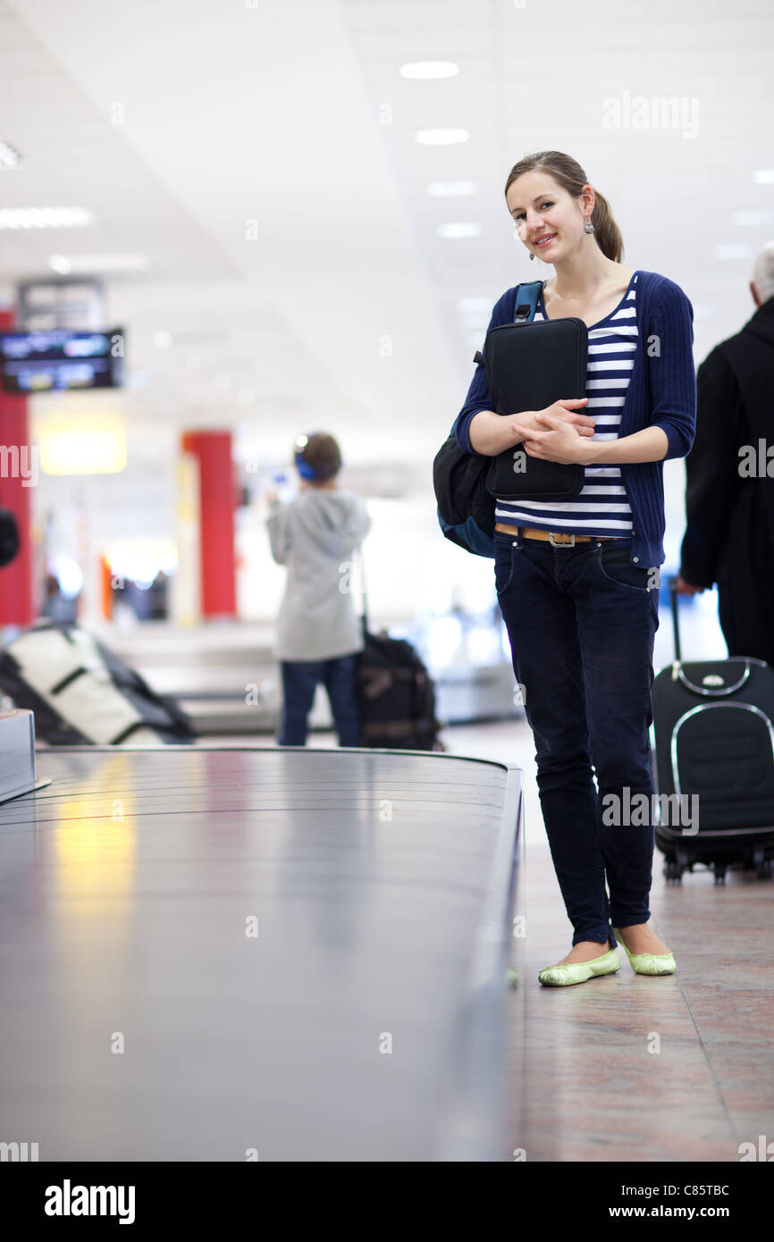 Baggage reclaim at the airport - pretty young woman taking her suitcase ...