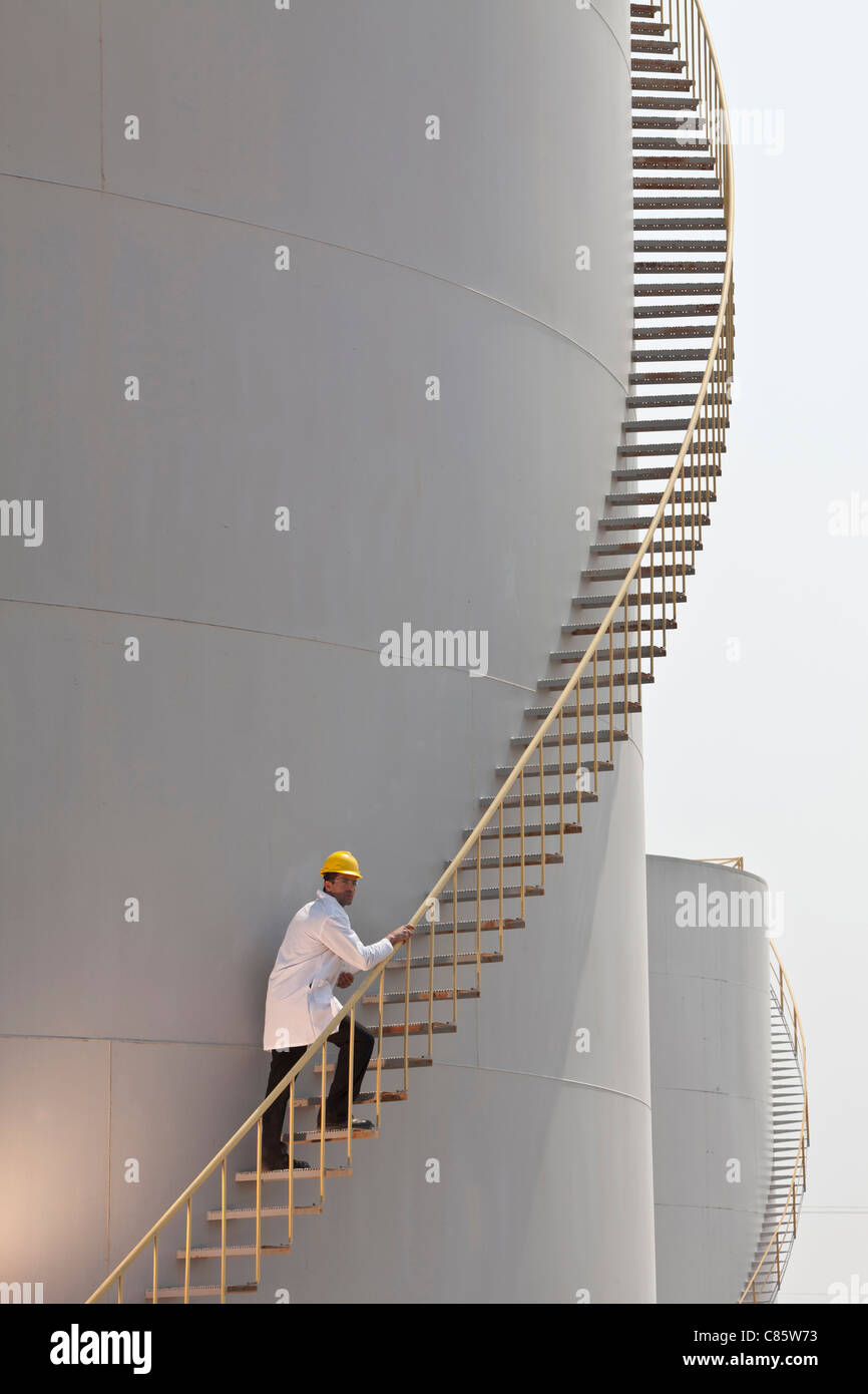 Caucasian worker climbing staircase on storage tank Stock Photo - Alamy