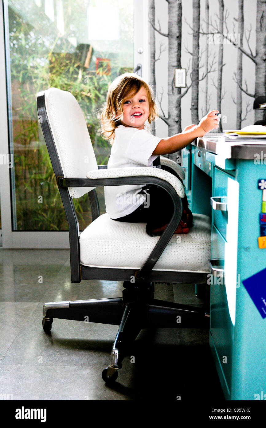 Little boy sitting at large desk Stock Photo - Alamy