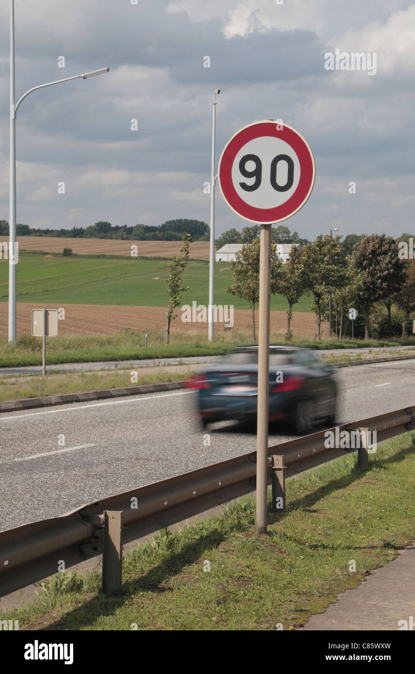 A car speeds past a 90km/h speed limit sign beside a rural road in ...