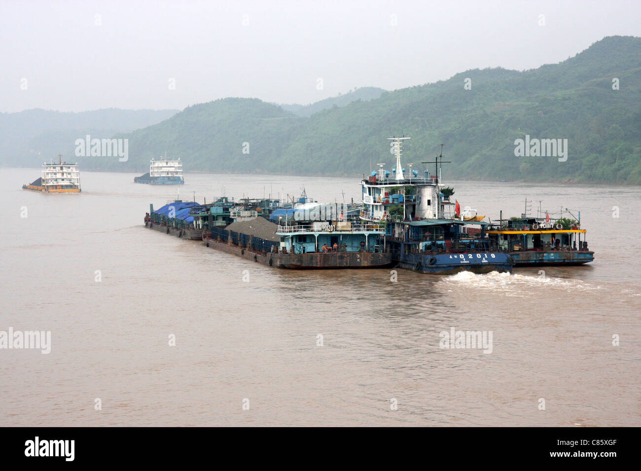 Several river boats being pushed upstream by one tug boat, Yangtze ...