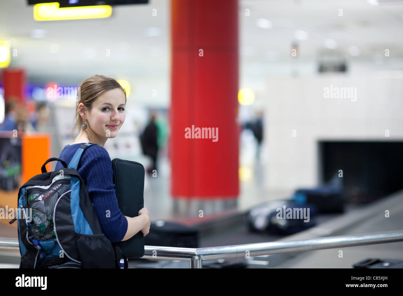 Baggage reclaim at the airport - pretty young woman taking her suitcase ...