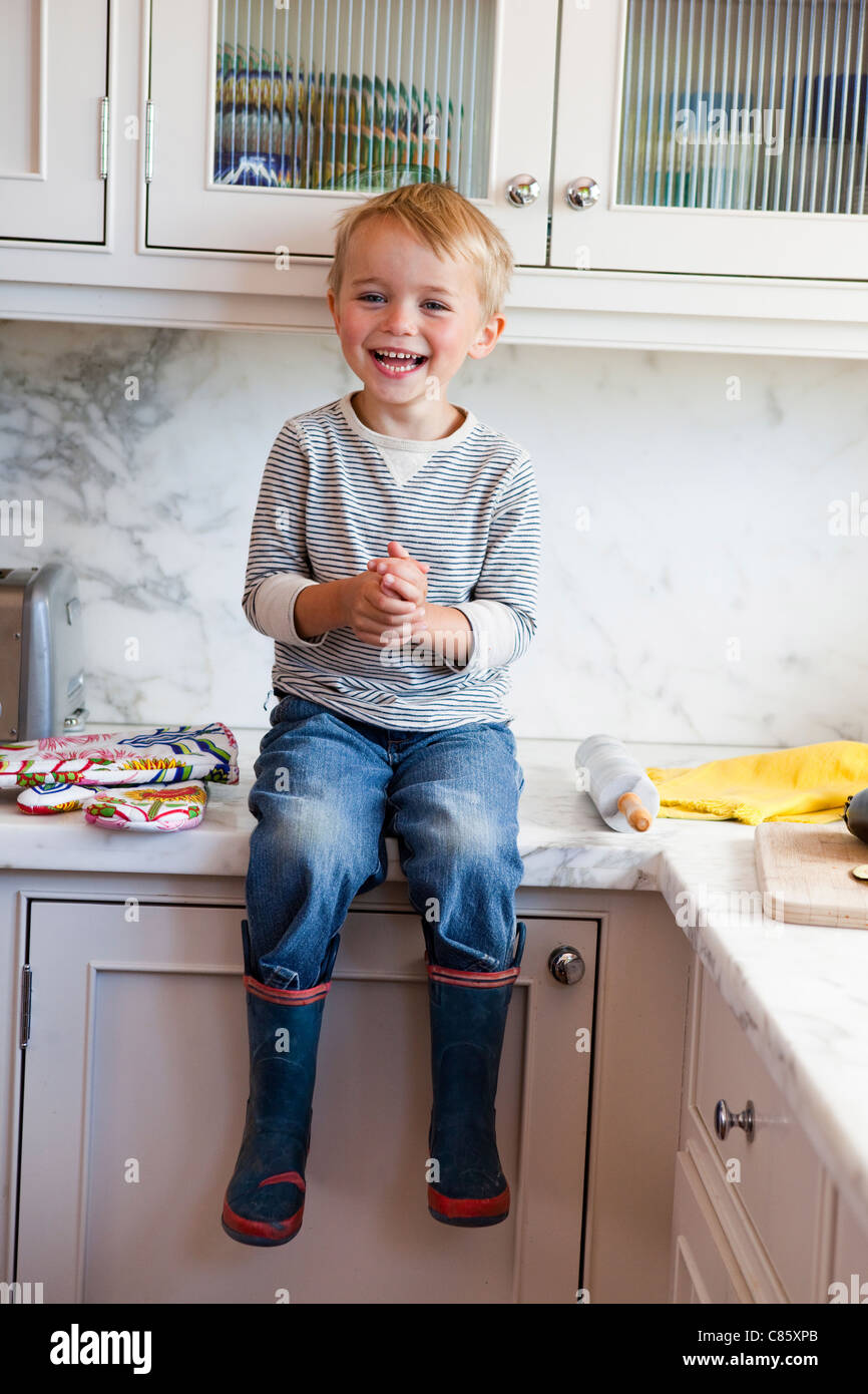 Laughing boy sitting on kitchen counter Stock Photo - Alamy