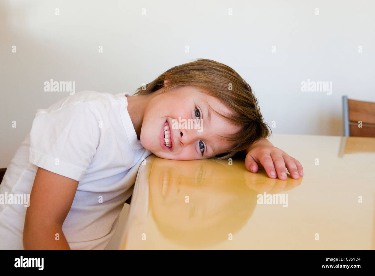 Smiling boy laying on table Stock Photo - Alamy