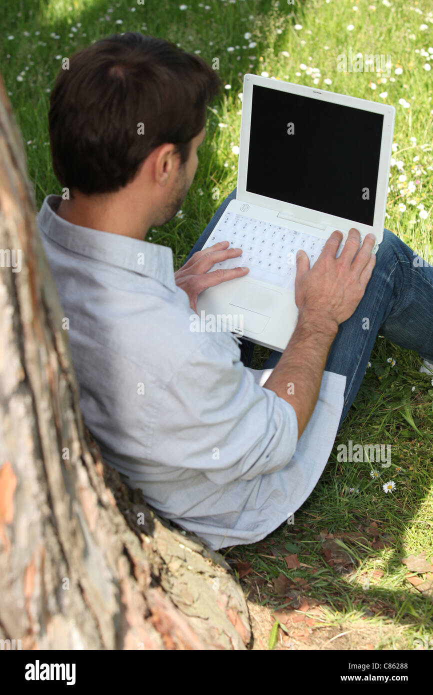 Man with a laptop under a tree Stock Photo - Alamy