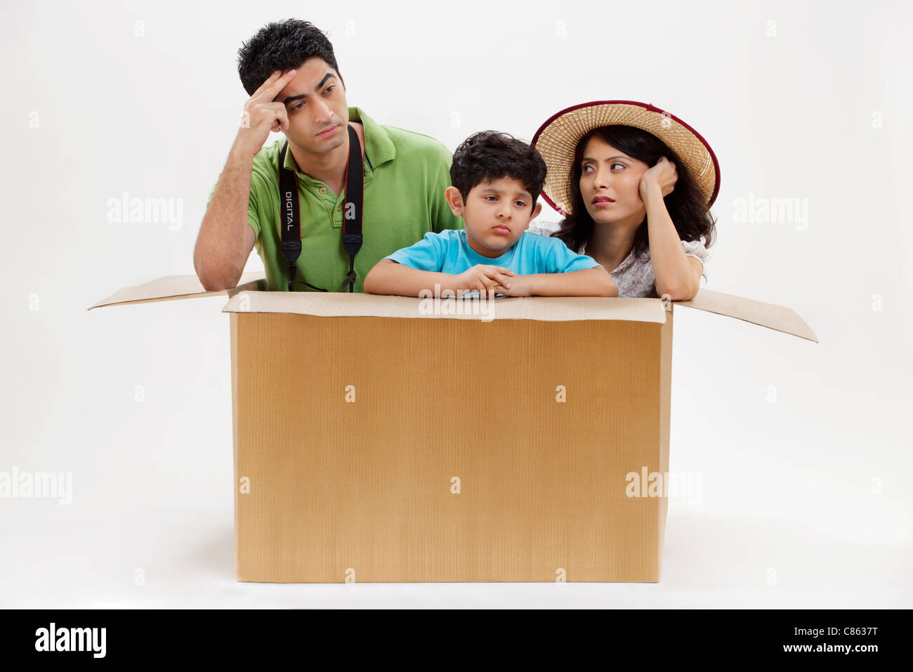 Bored young couple sitting inside cardboard box with little son Stock ...