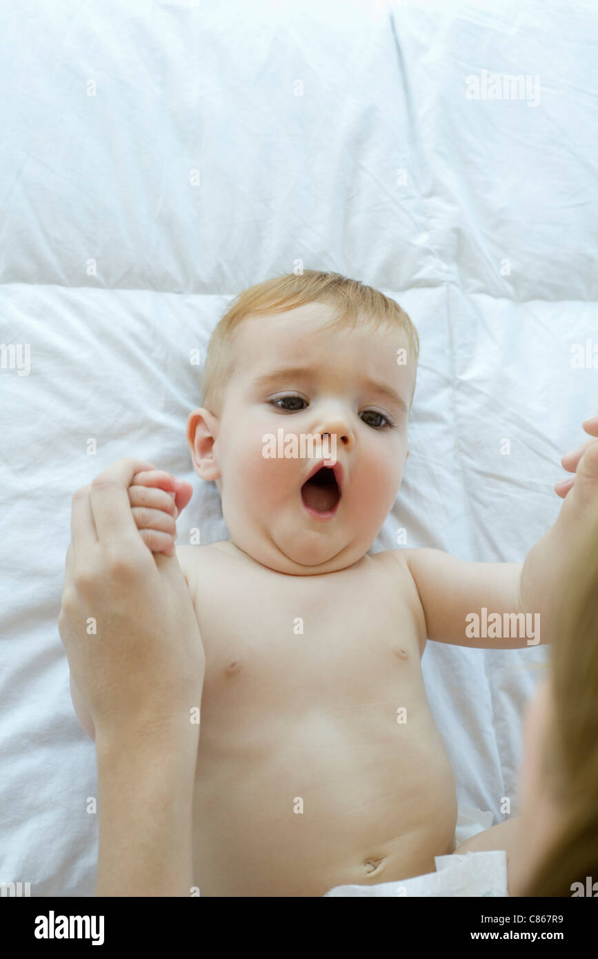 Baby lying on back, playing with mother Stock Photo - Alamy