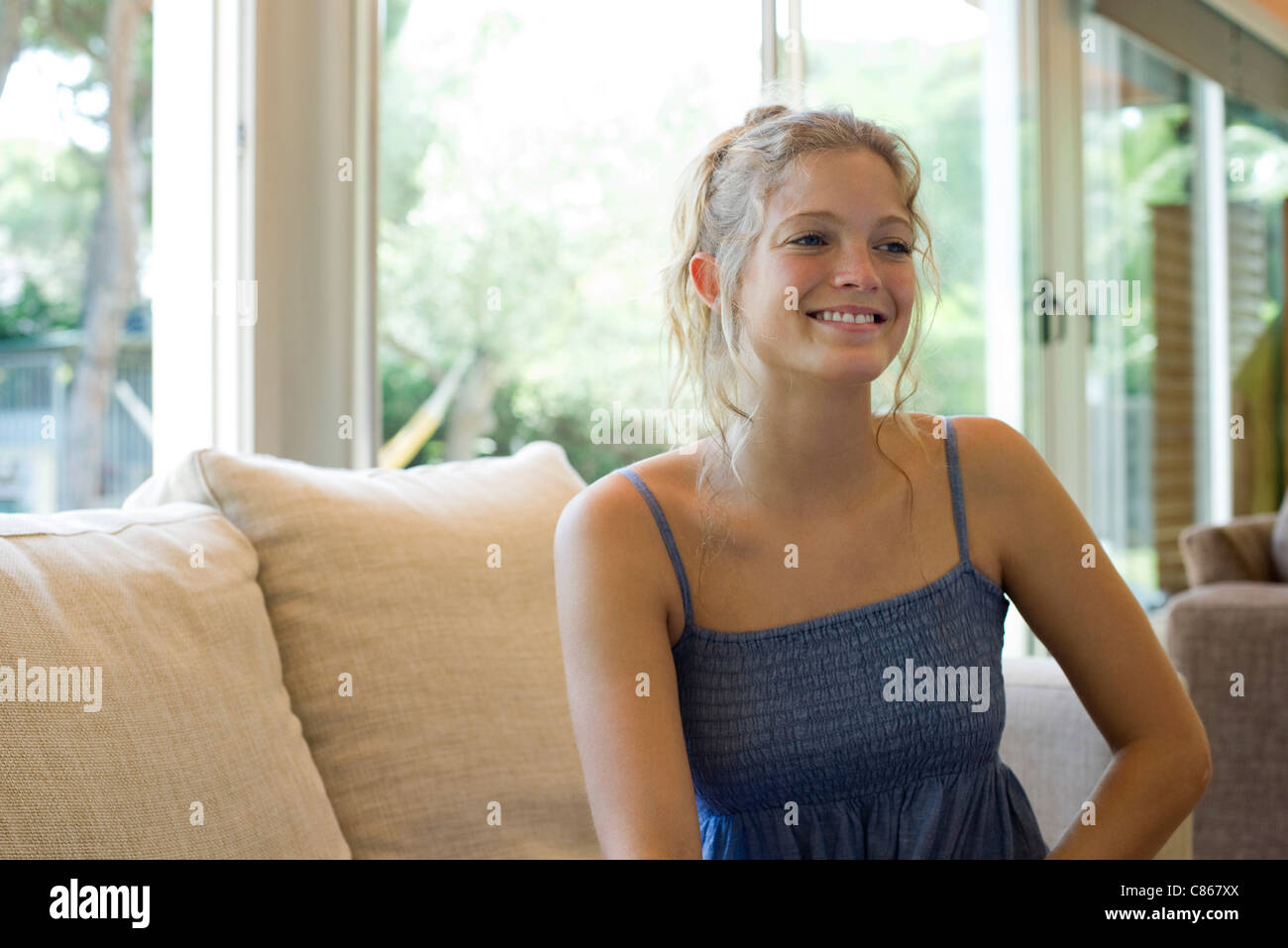Woman sitting on sofa, smiling Stock Photo - Alamy