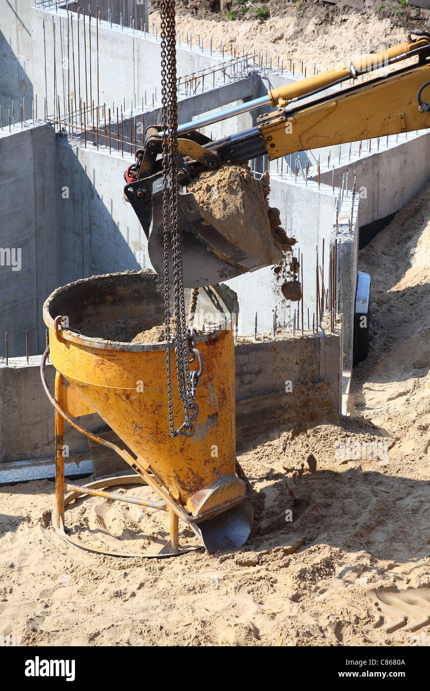 digger, excavator construction building site pouring concrete in form ...