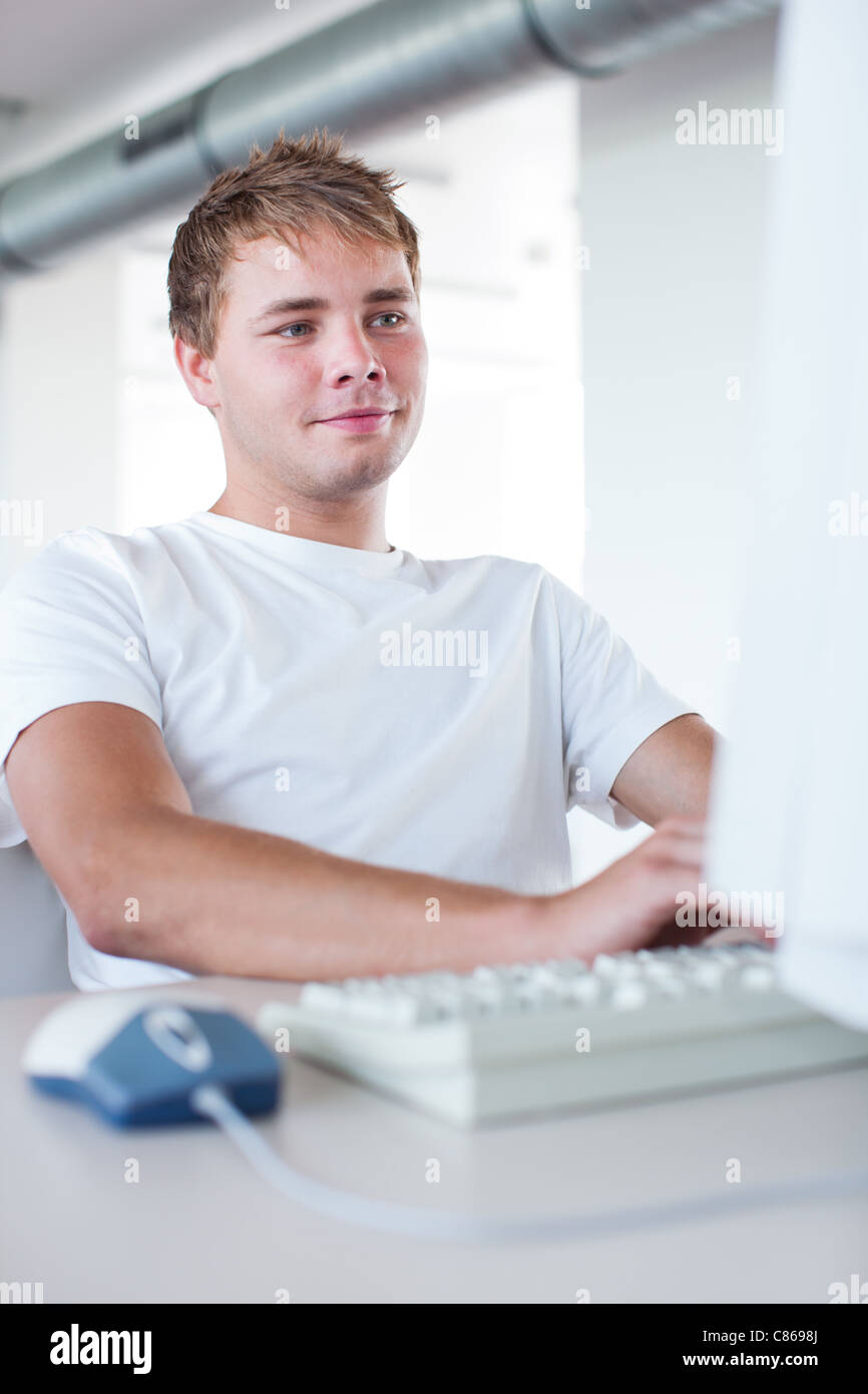 handsome college student using a computer in a college/university ...