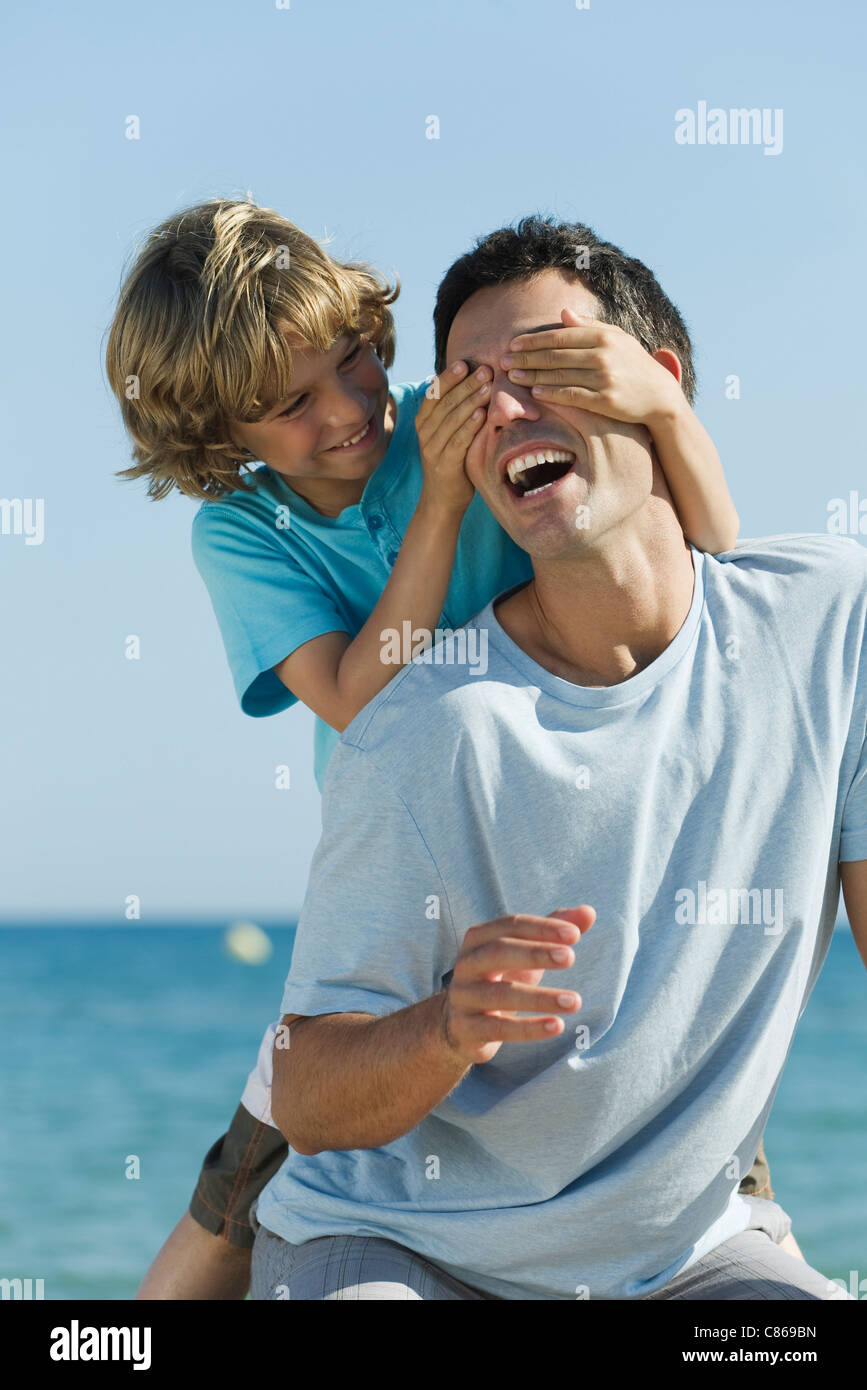 Boy covering father's eyes with hands Stock Photo - Alamy